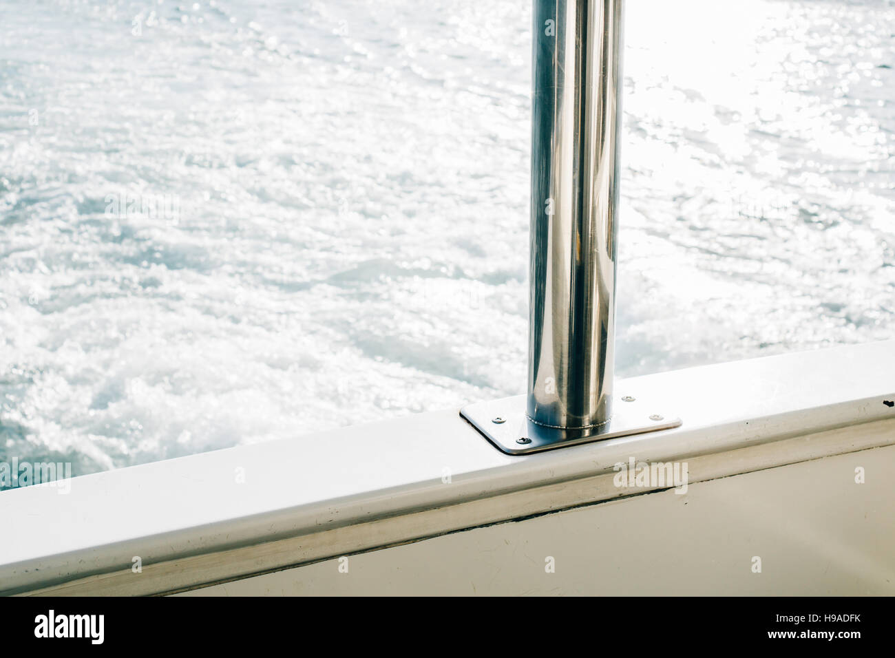 Closeup on a metallic silver railing of a boat with water in the ...