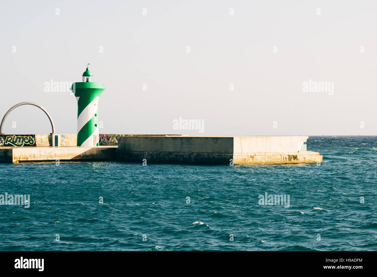 A green and white striped lighthouse on the Mediterranean Sea in ...