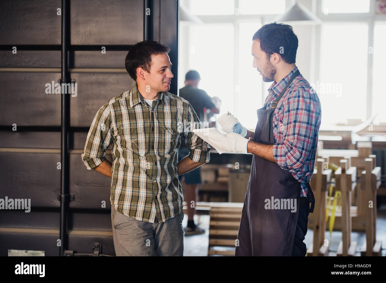 Two carpenters are talking while holding papers and ruler. One of them ...