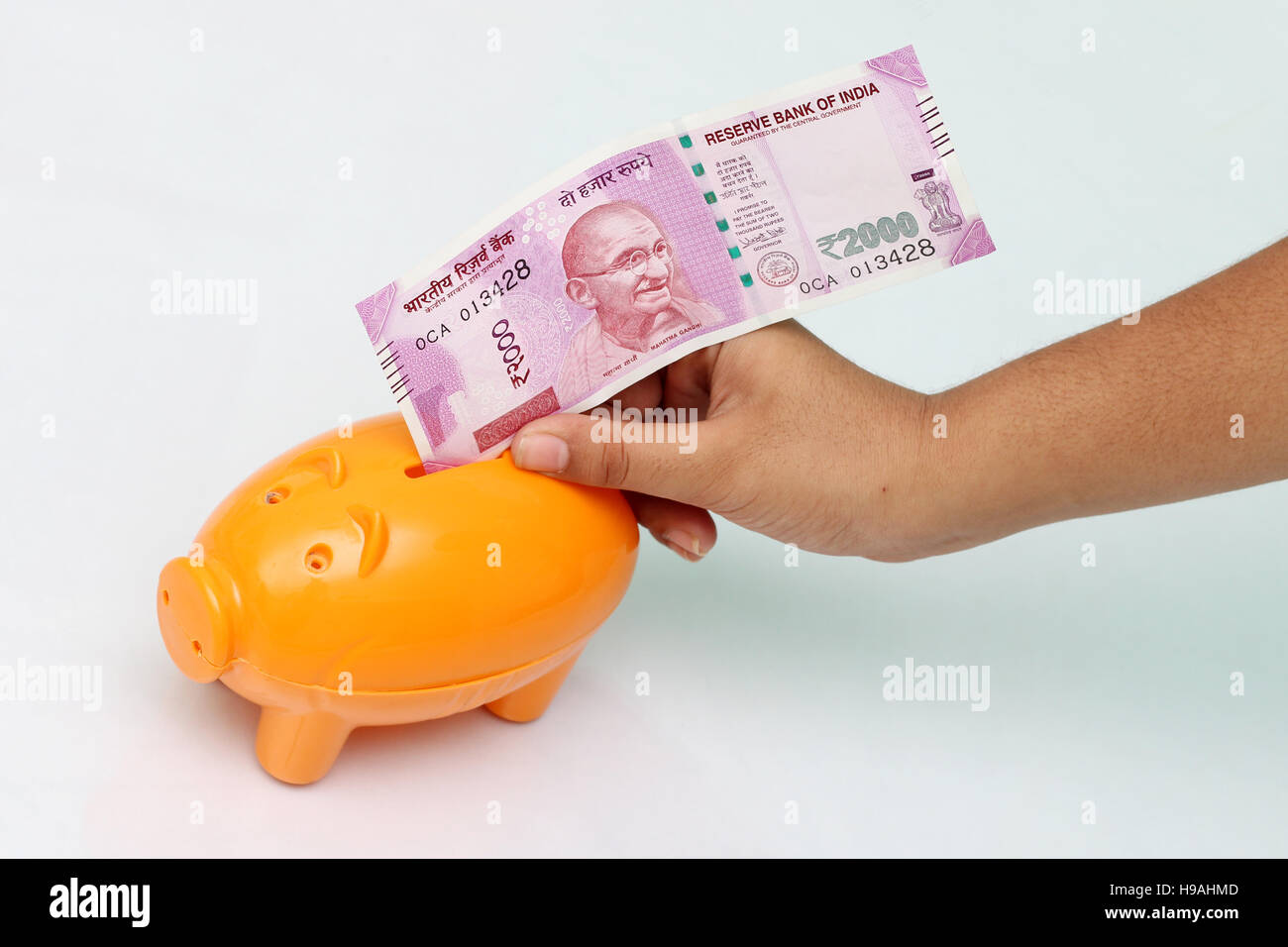 Saving money. Hand putting money into piggy bank. New Indian currency ...