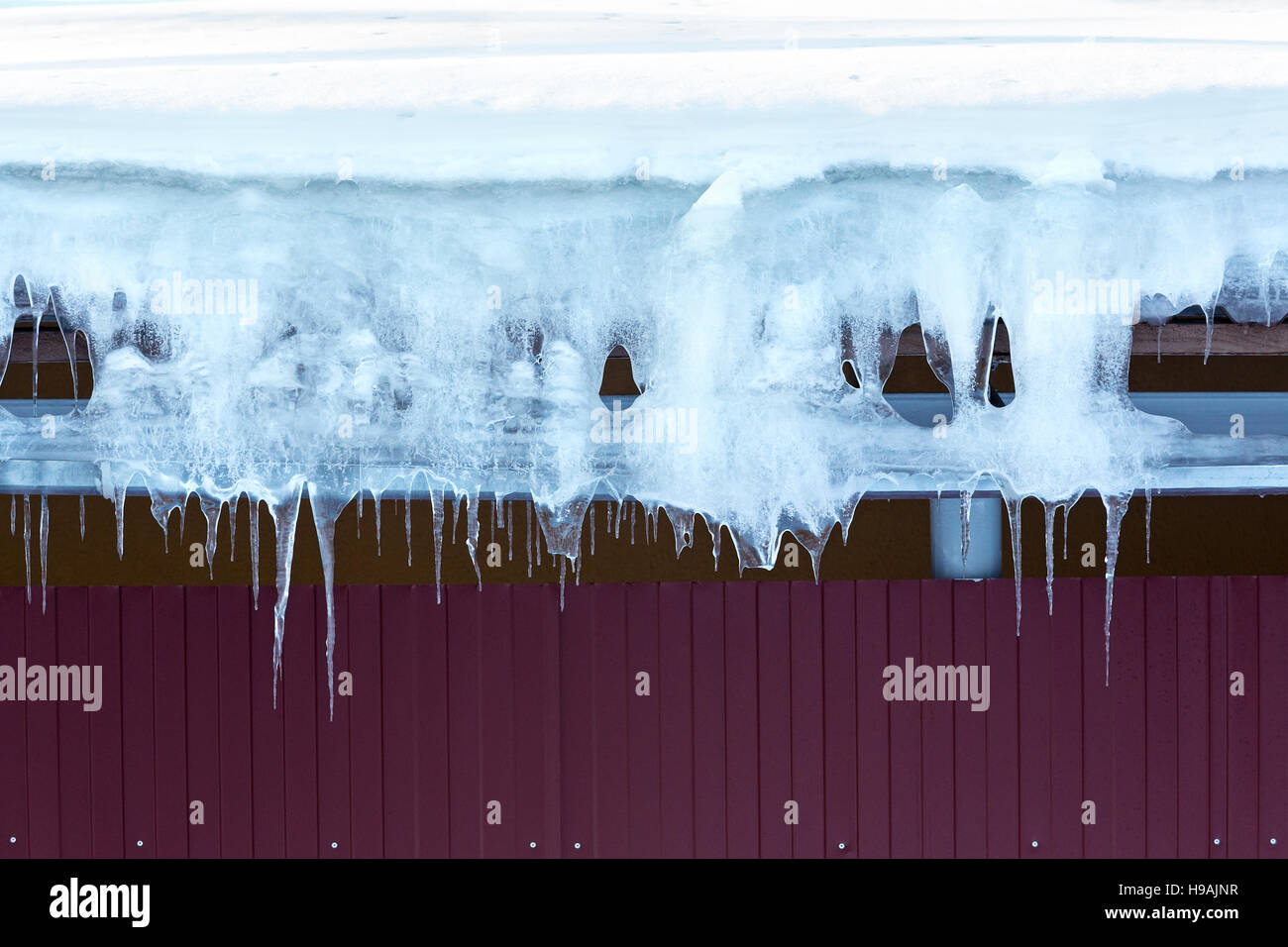 Snow and icicles hanging from the roof Stock Photo - Alamy