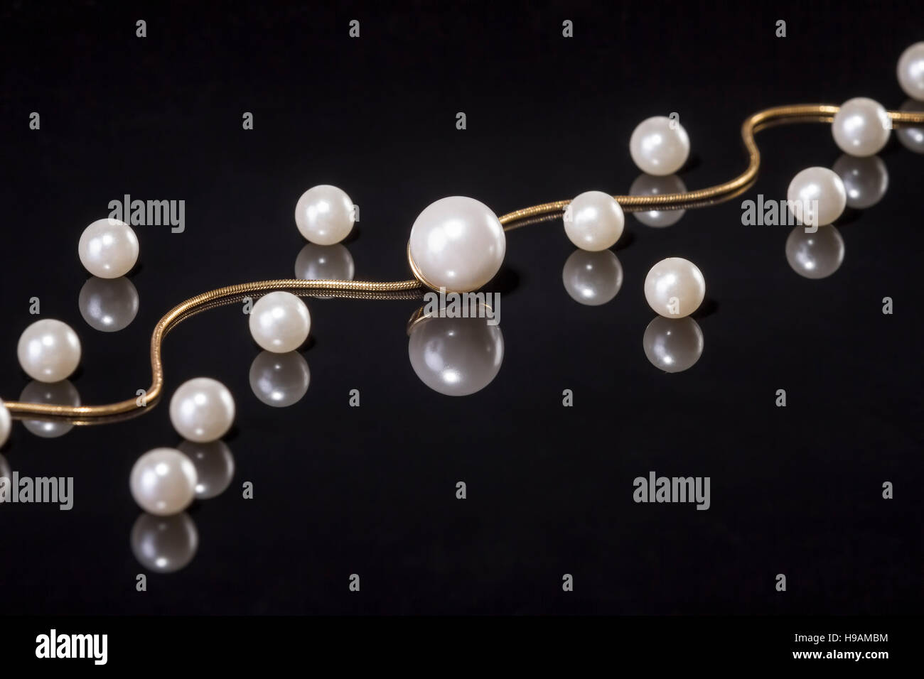 White pearls necklace on black background. Focus on the big pearl ...