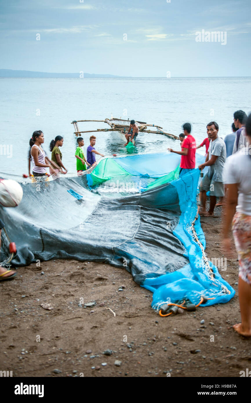 Villagers hauling in fishing nets on Dauin Beach, south of Dumaguete ...