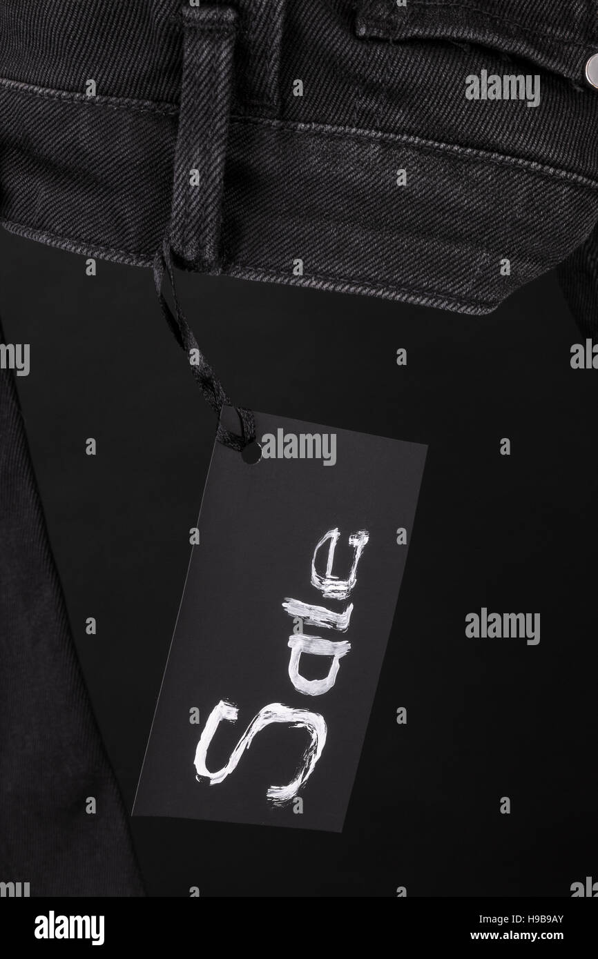 Sale sign hanging on black jeans with black background. Friday sale ...