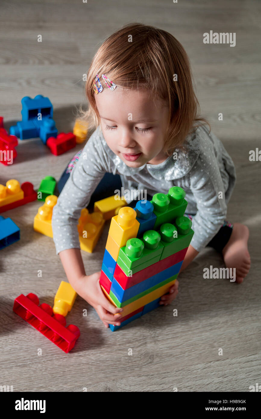 Child girl having fun and build of bright plastic construction blocks ...