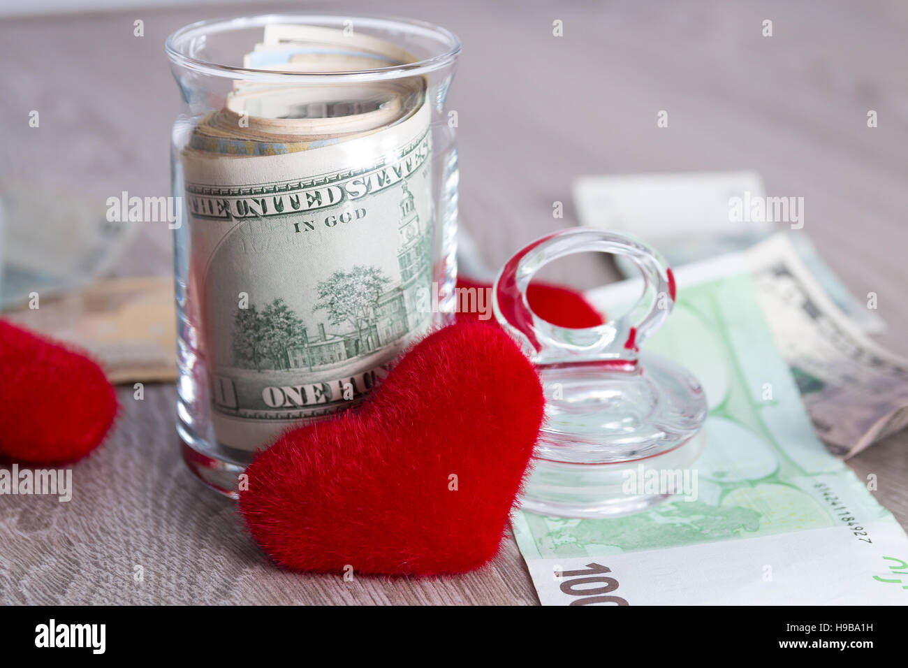 Money and red hearts. Dollars in open jar on grey wooden background ...