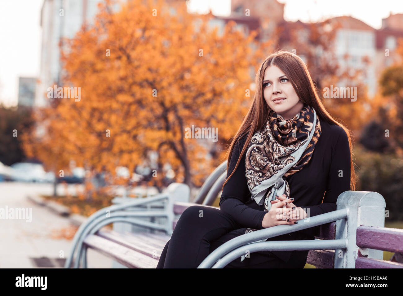 Young woman sitting at the bench Stock Photo - Alamy