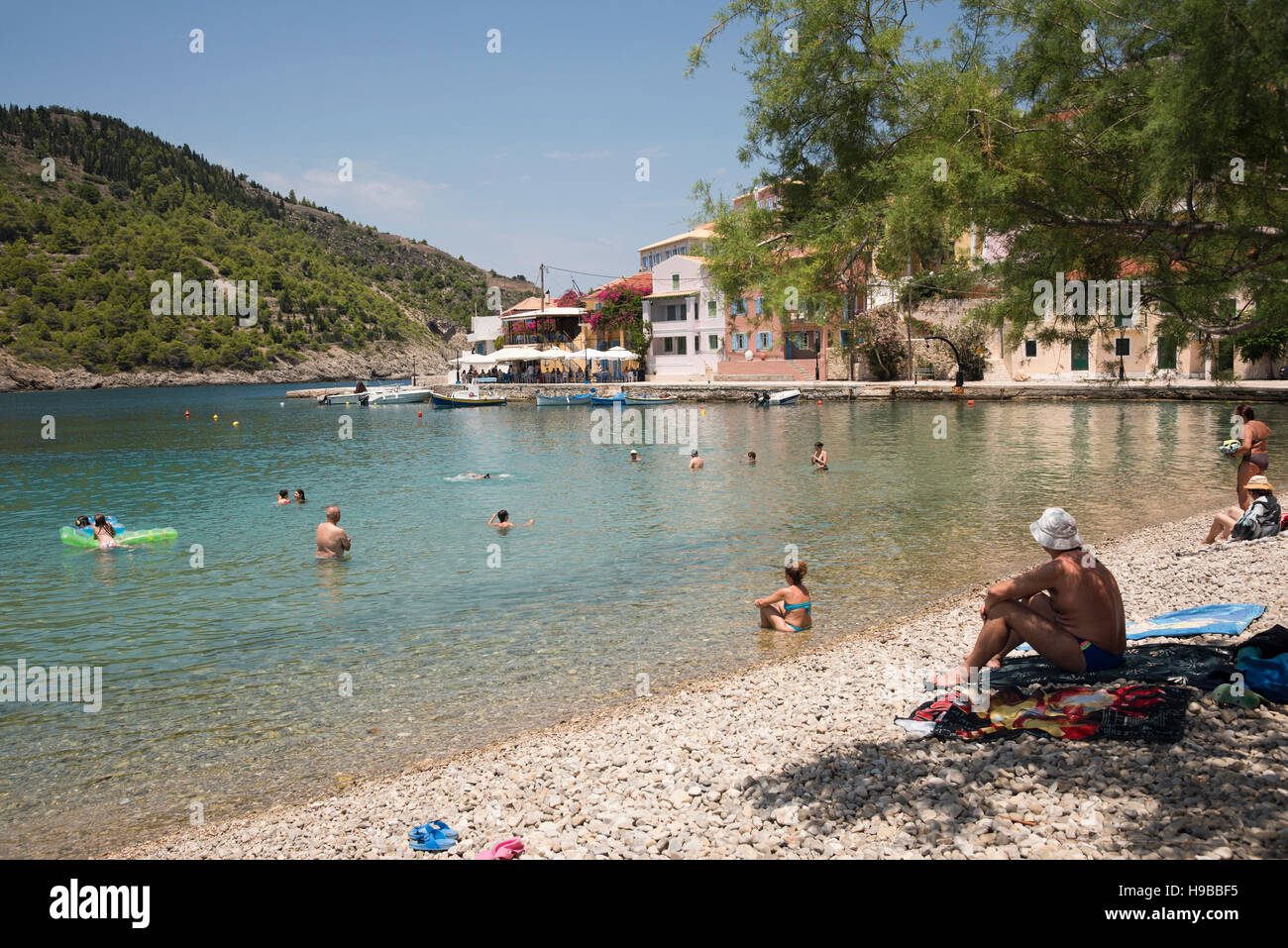 Pebbled beach with bathers, in the idyllic village of Assos, on the ...