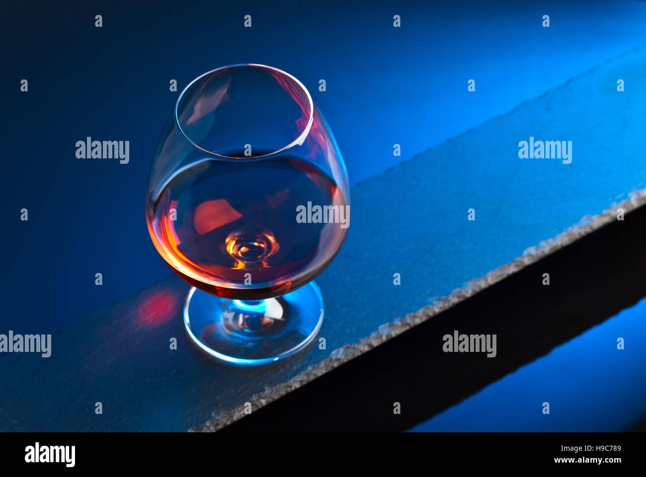 Snifter with brandy on a blue background Stock Photo - Alamy