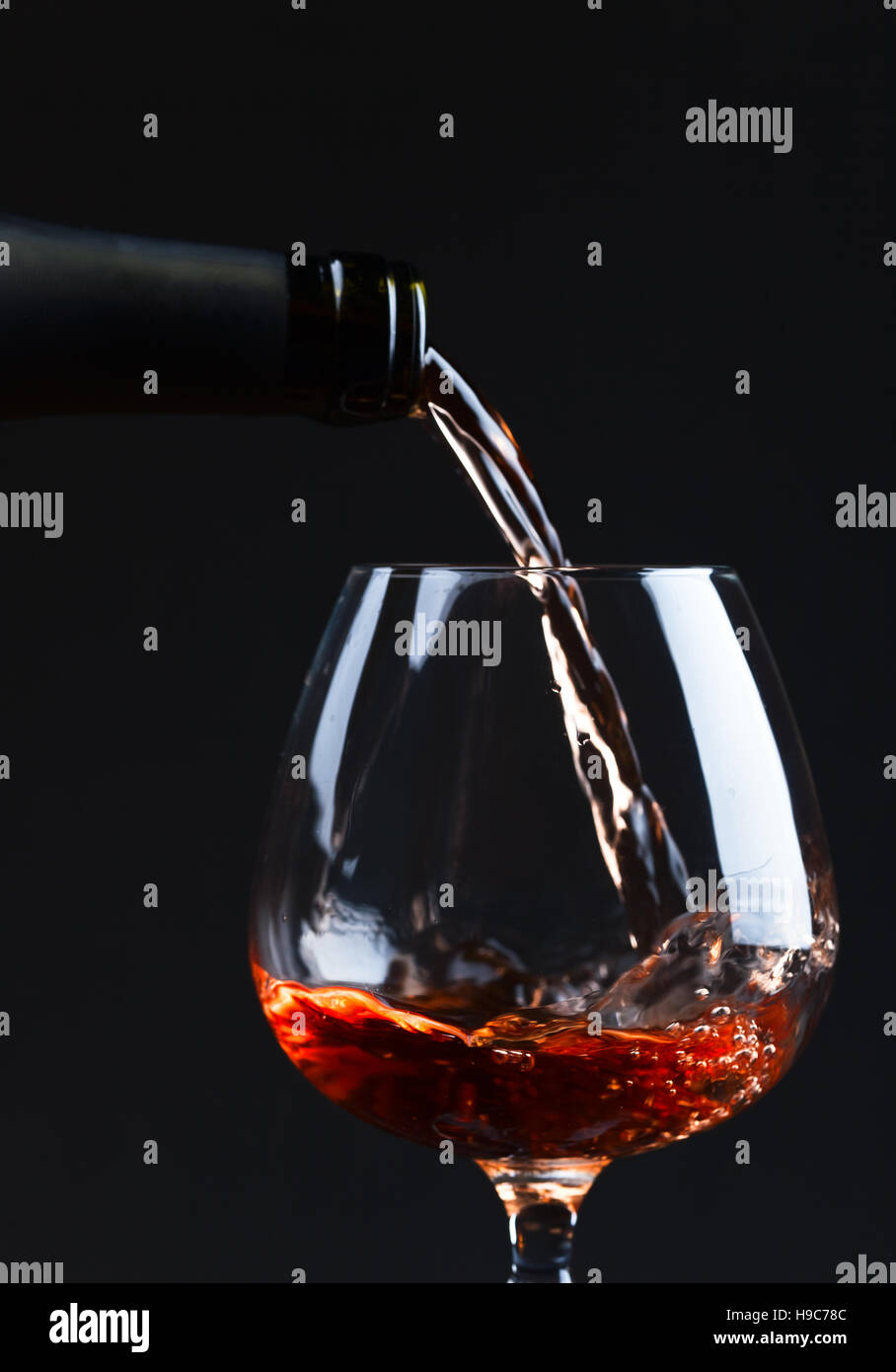 Snifter with brandy on a black background Stock Photo - Alamy