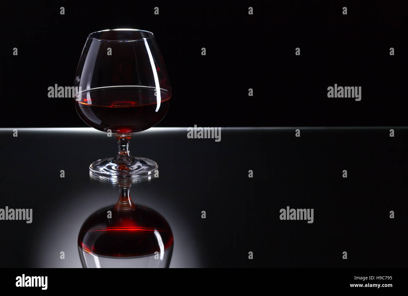 Snifter with brandy on a reflective background Stock Photo - Alamy