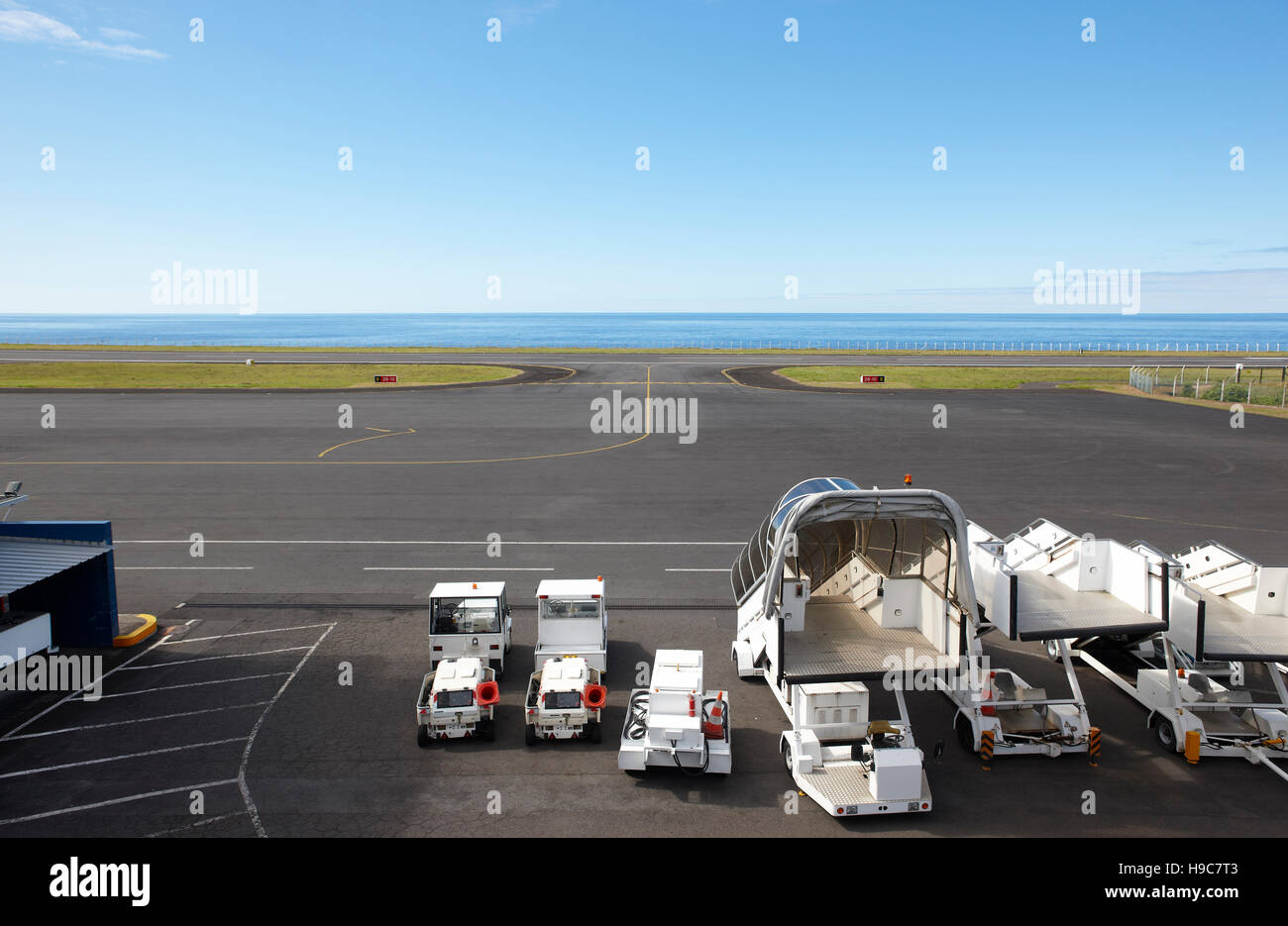 Airport runway close to the ocean with auxiliary vehicles. Horizontal ...