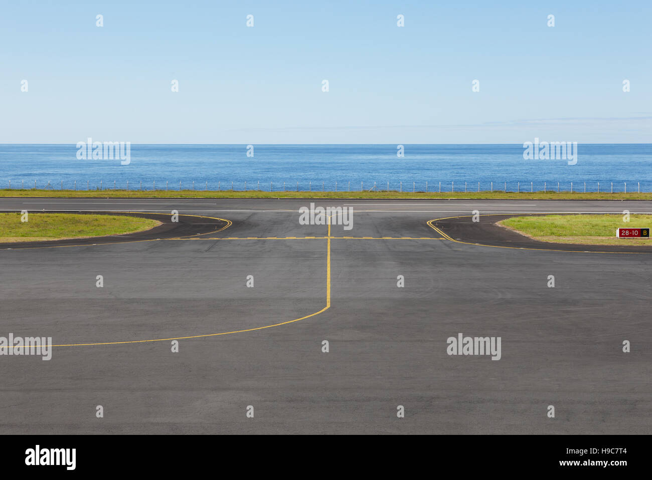 Airport runway close to the ocean with lines and fence. Horizontal ...