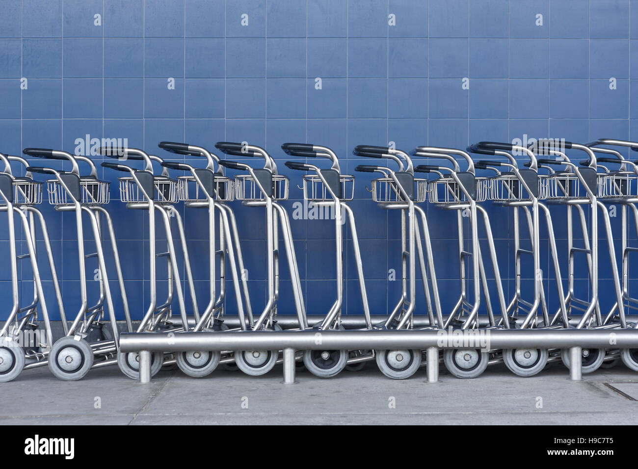 Airport trolley parking lot with empty trolleys and blue wall ...
