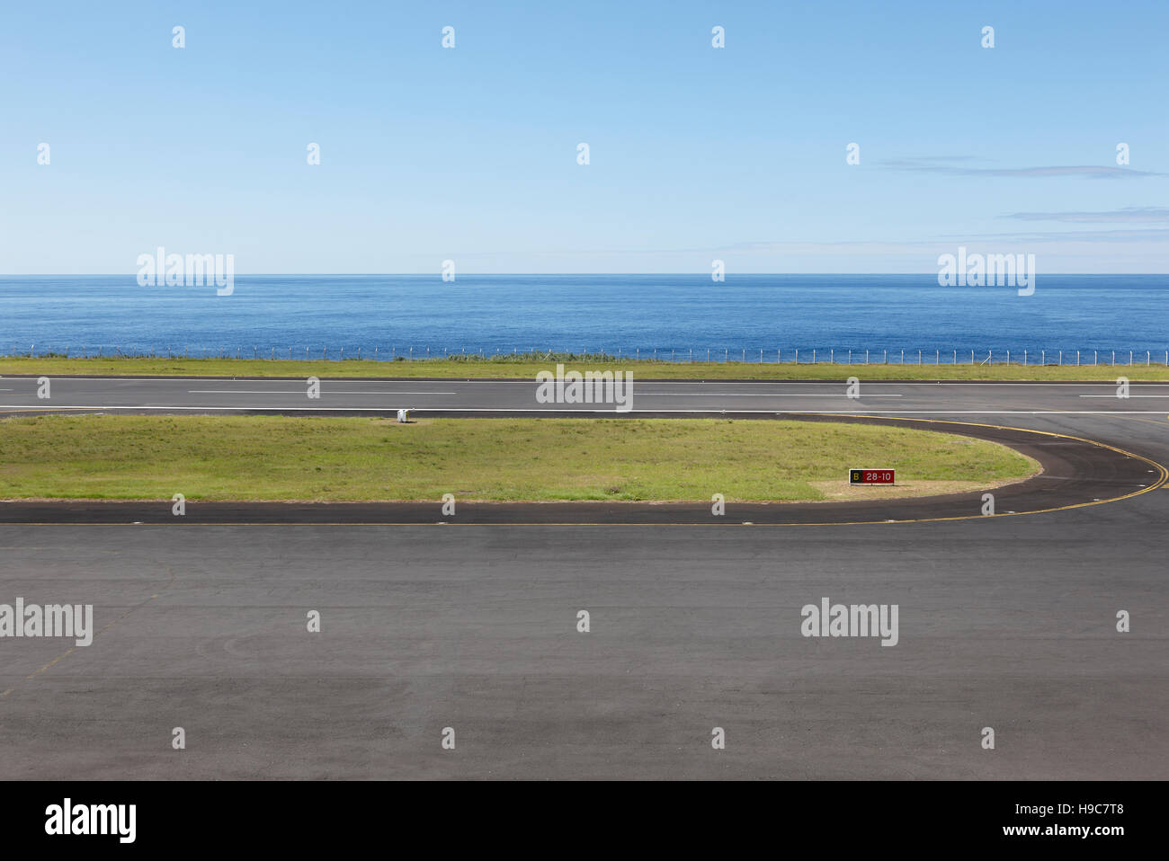 Airport runway close to the ocean with lines and fence. Horizontal ...