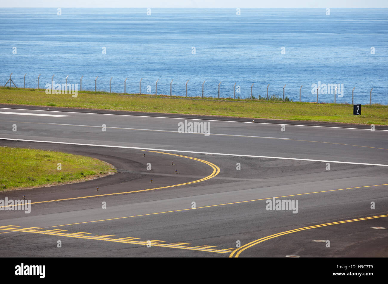 Airport runway close to the ocean with lines and fence. Horizontal ...