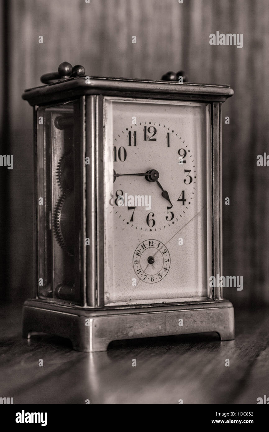 An old desk top clock with analog hour and minute hand on a shelf Stock ...