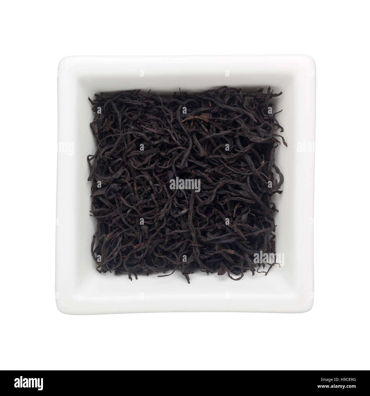 Chinese black tea leaves in a square bowl isolated on white background ...