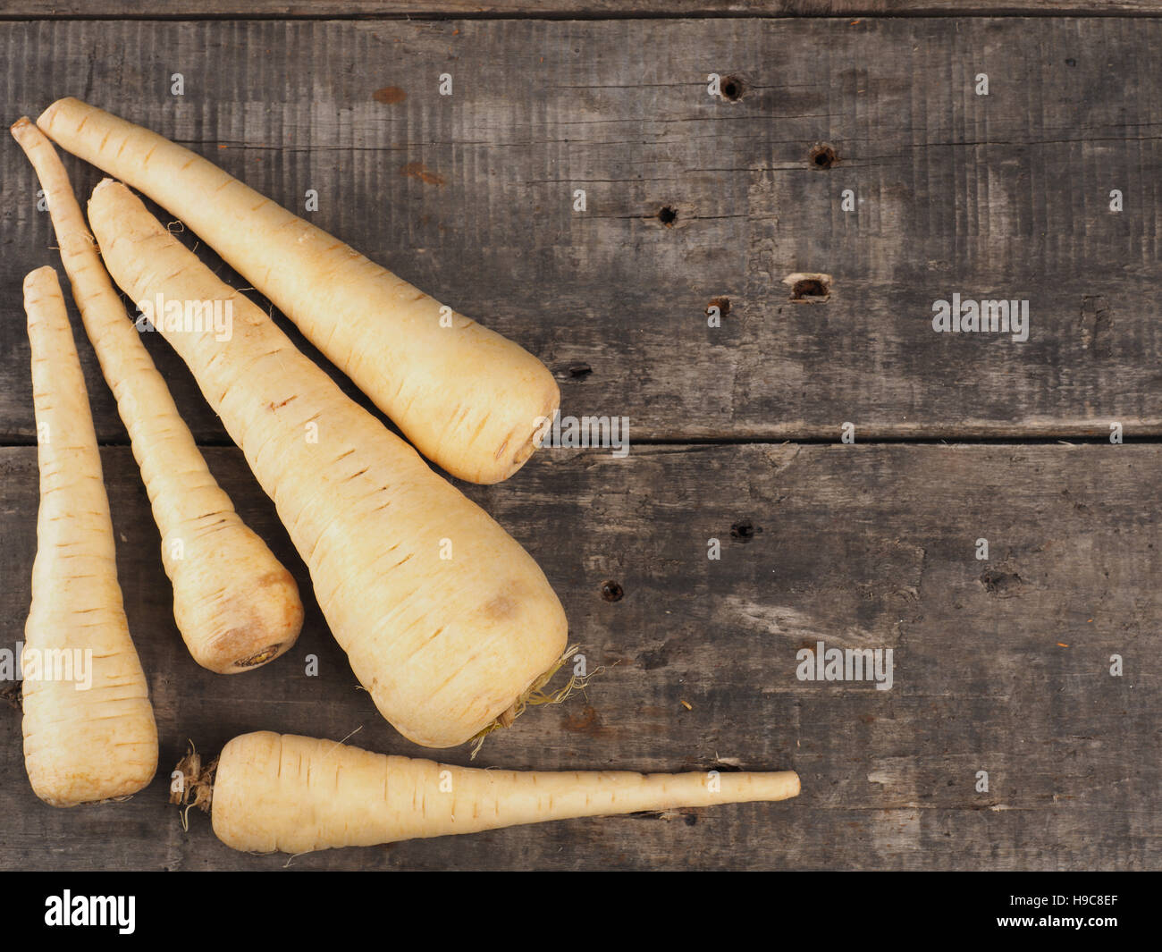 Five raw parsnip on a wooden kitchen table, view from above Stock Photo ...