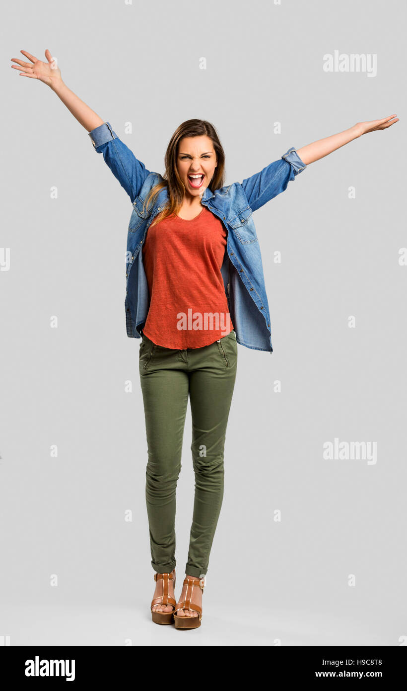 Beautiful happy woman with arms up over a gray background Stock Photo ...