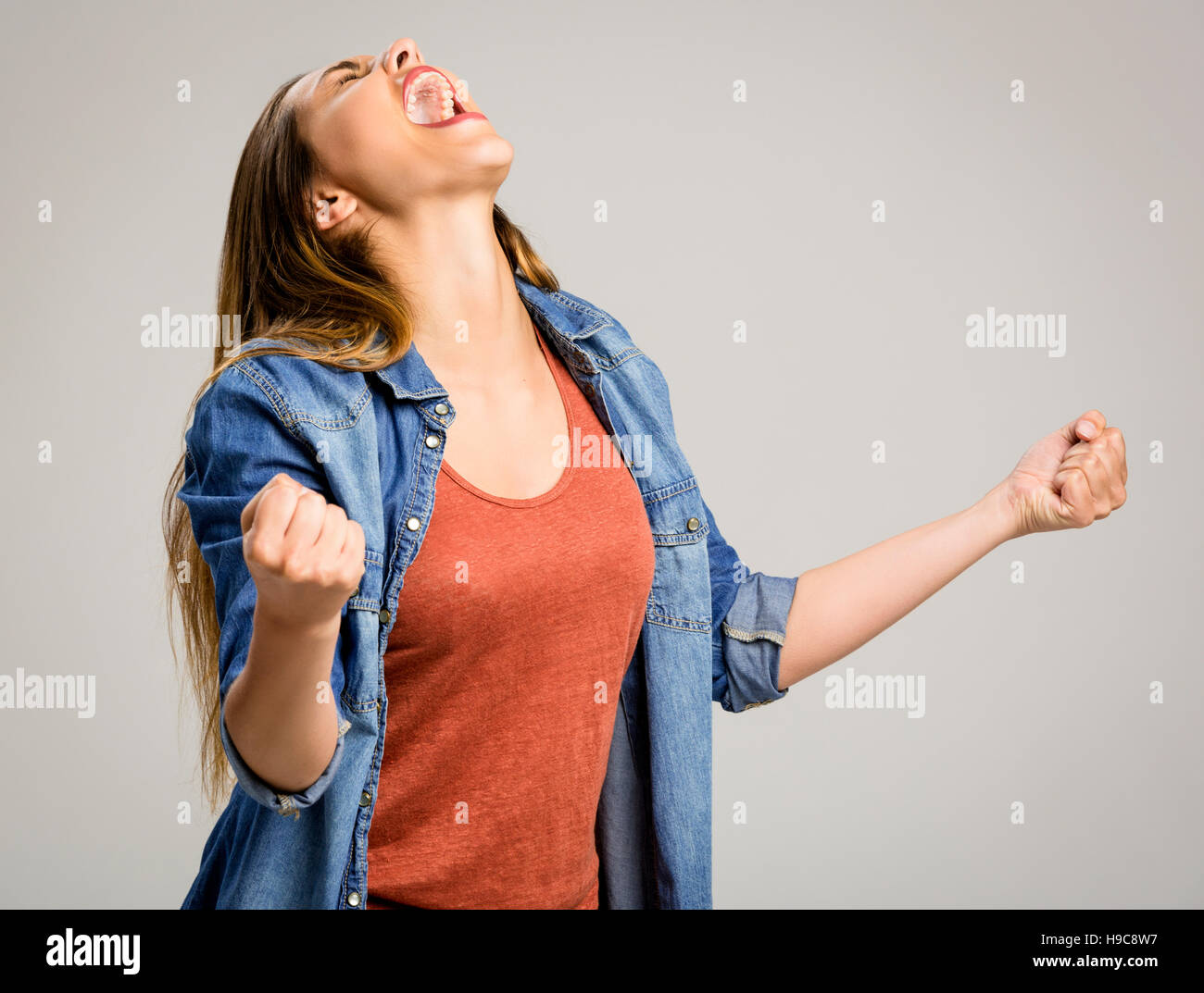 Beautiful happy woman with arms up over a gray background Stock Photo ...