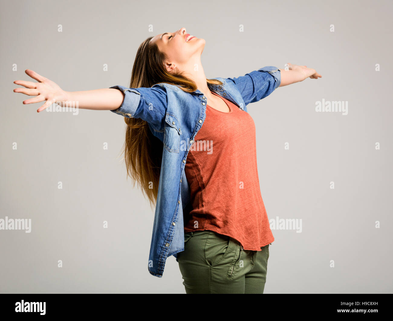 Beautiful happy woman with arms up over a gray background Stock Photo ...