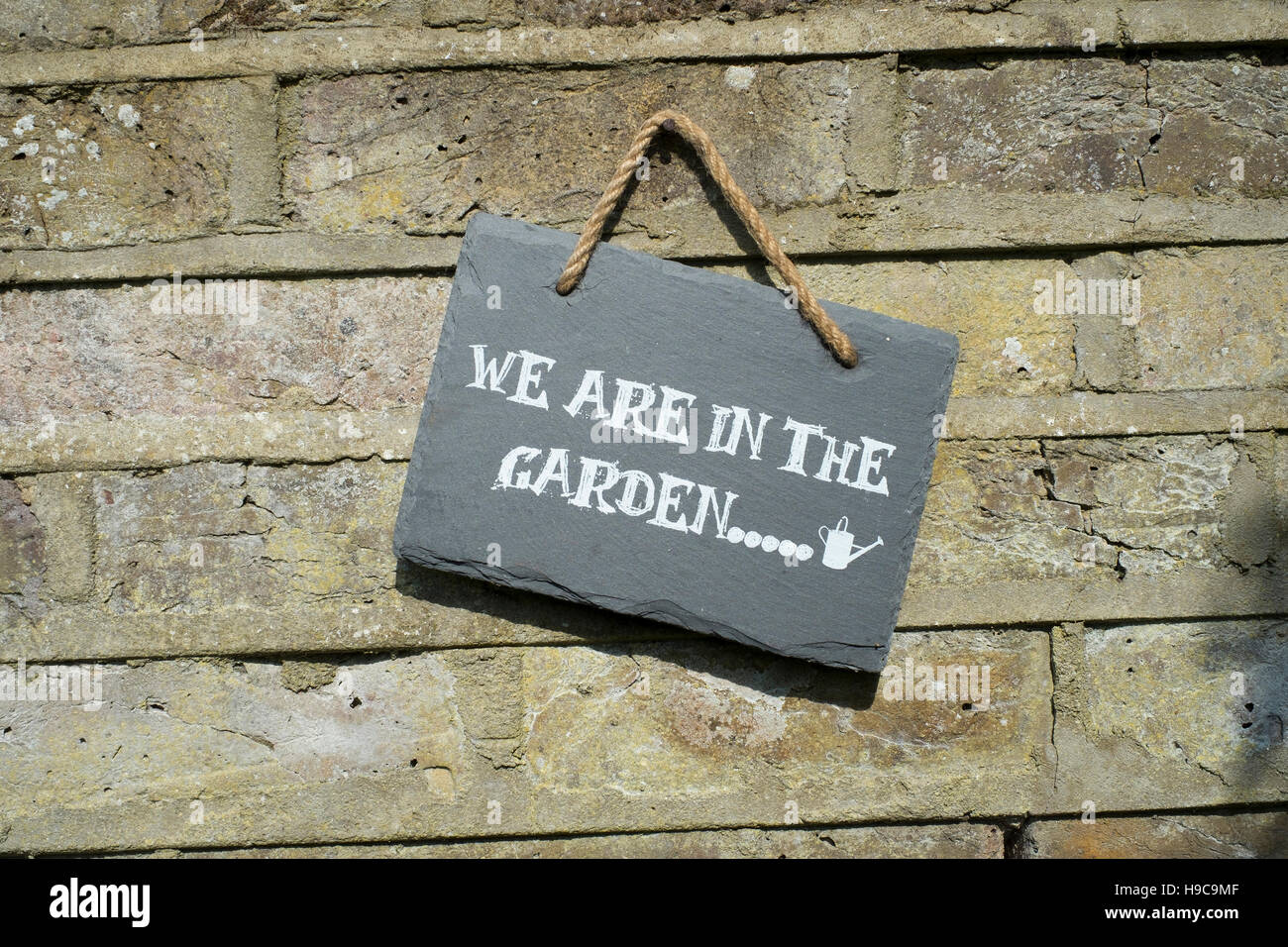 "We are in the garden" hand painted slate sign hanging on an ageing ...