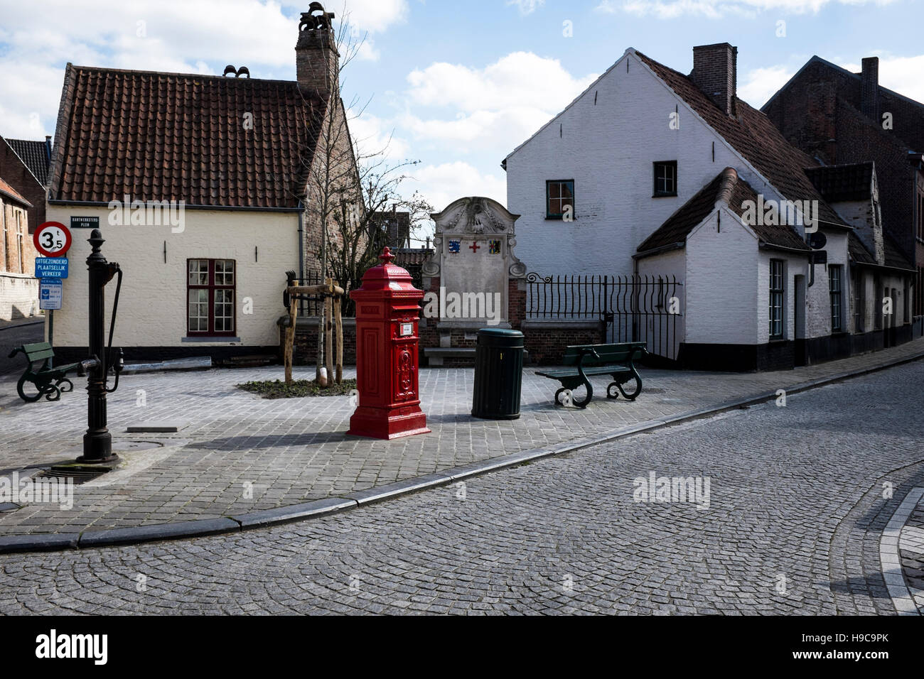 A hand water pump, post box and bench in a cobbled street in Bruges ...