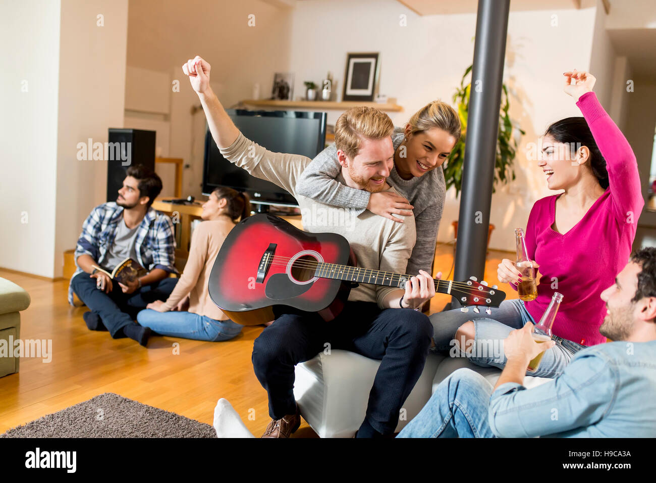 Happy friends playing guitar and listening to music at home Stock Photo ...