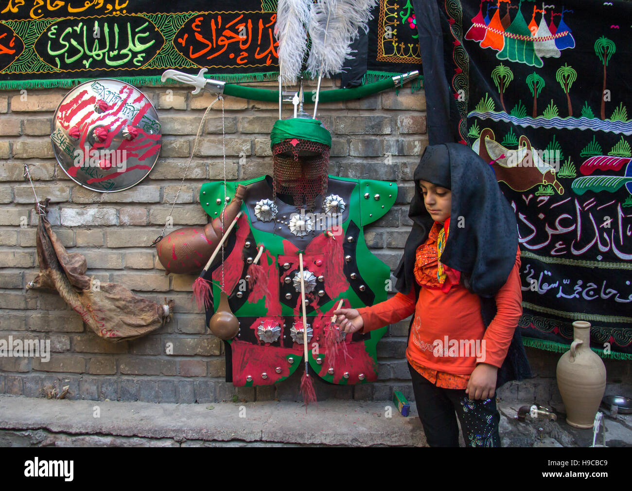 A litle girl stands in front imam hussein clothes during the chehel ...