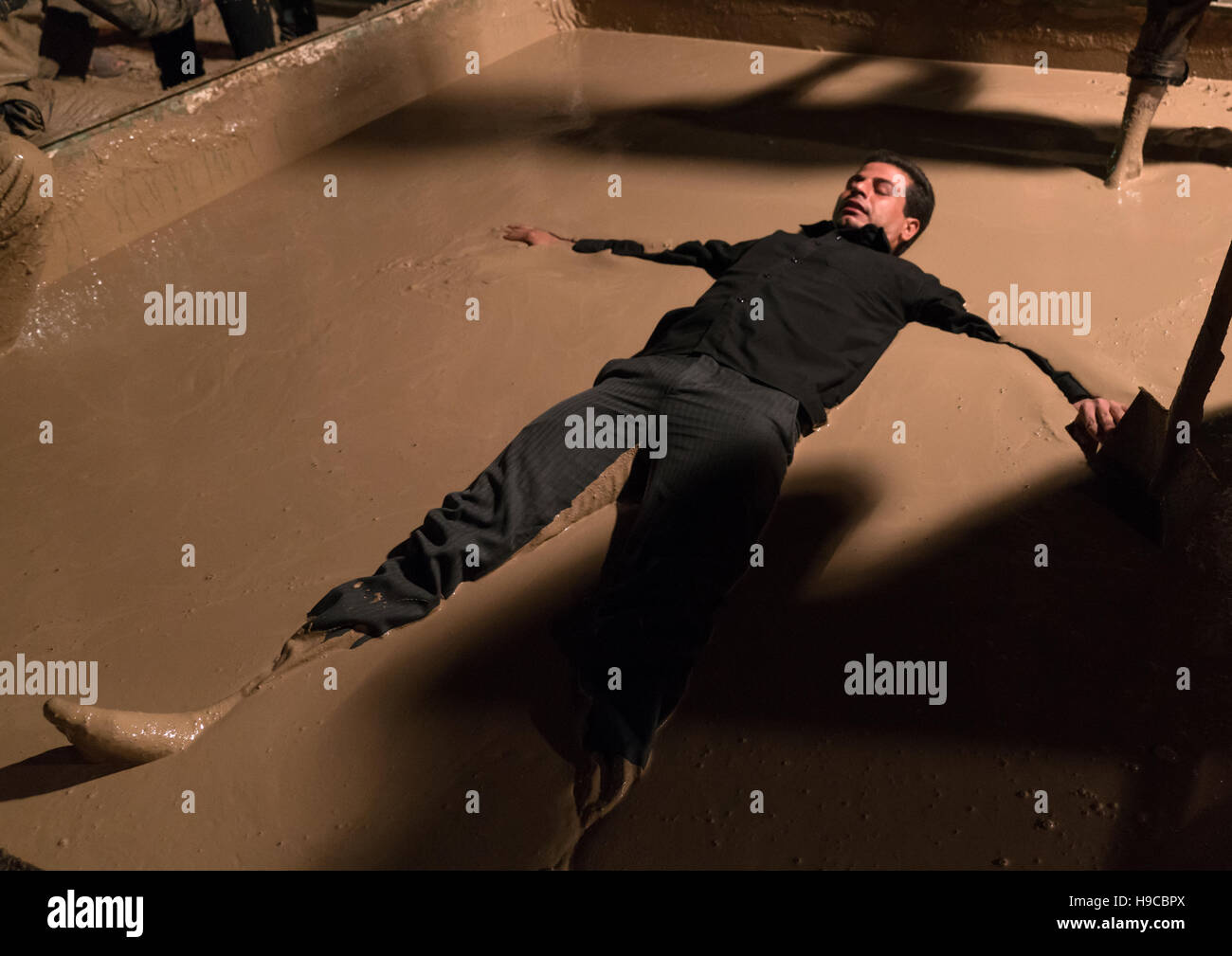 An iranian shiite muslim man rolls lies in a mud pond as he takes part ...