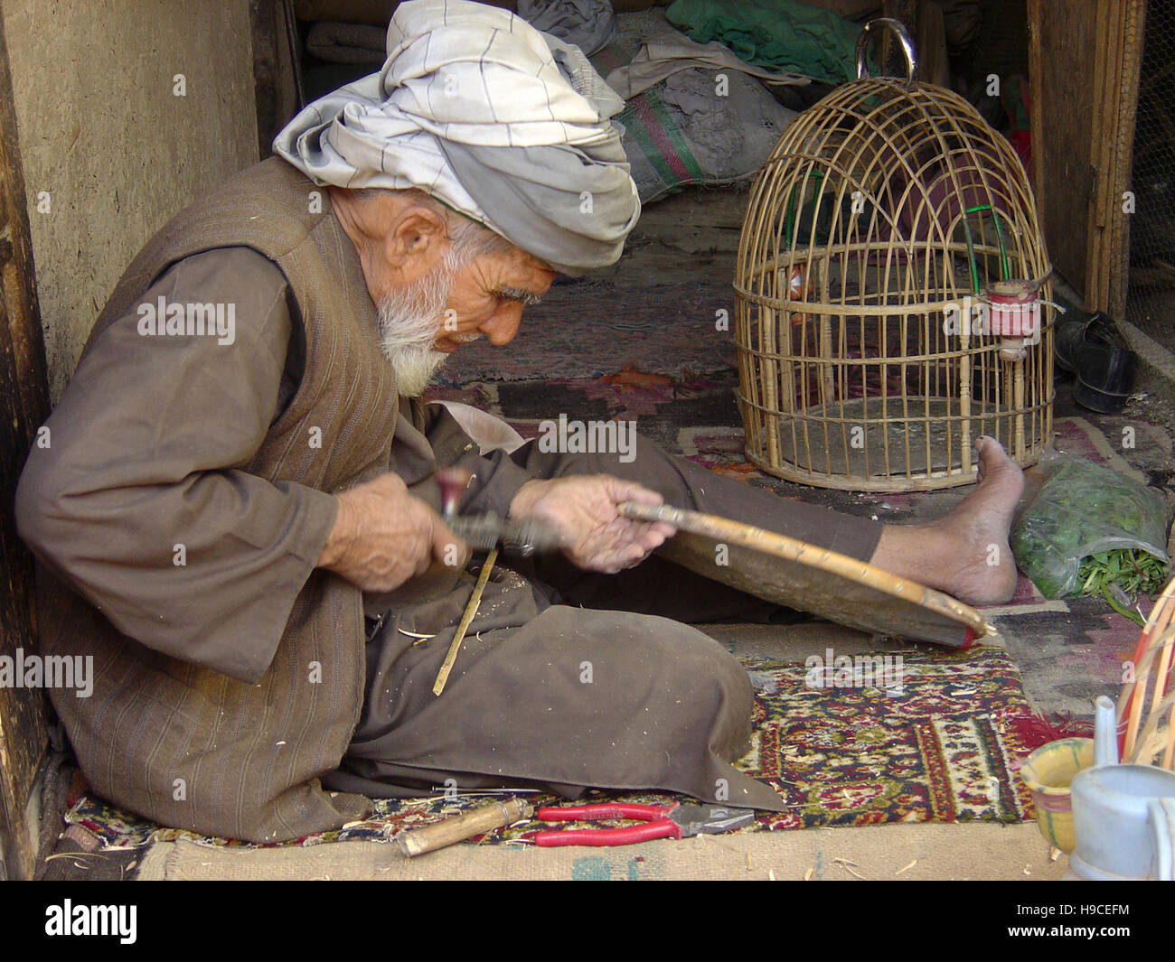 28th May 2004 An old man wearing a lungee (turban) makes wicker bird ...