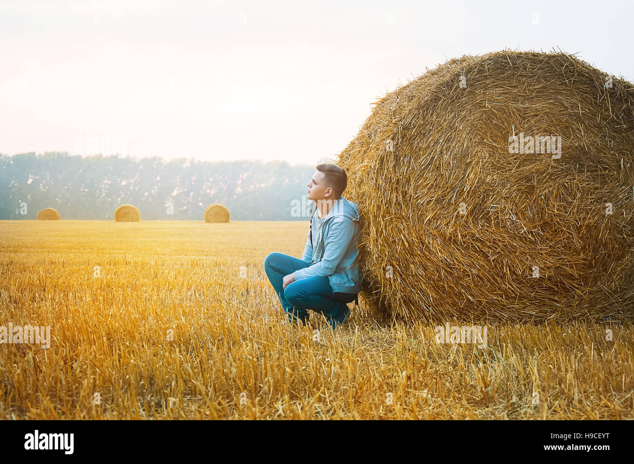 Young beautiful man seating near straw bales Stock Photo - Alamy