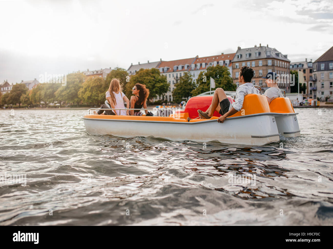 Outdoors shot of teenage friends sitting in pedal boat. Group of people ...