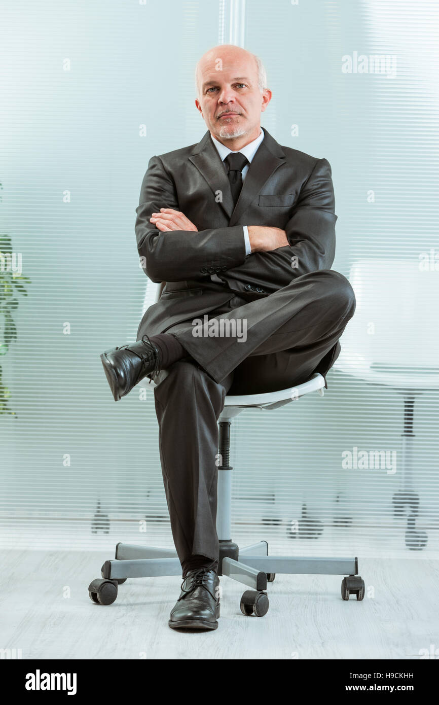 stern office worker sitting on his chair and looking you seriously ...