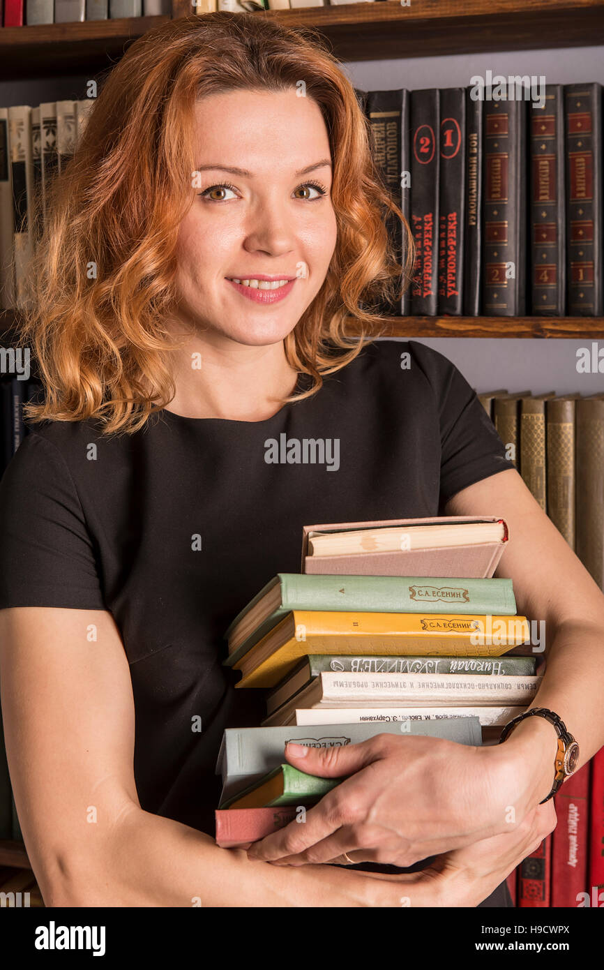 Girl with dark hair is reading a book in the library Stock Photo - Alamy