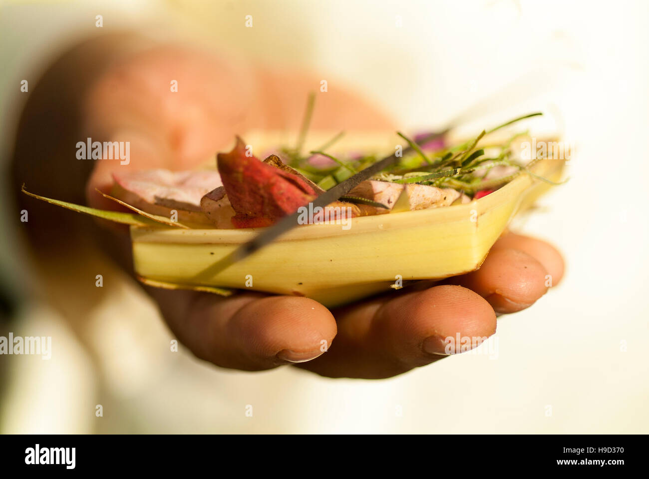 A canang sari religious offering in a bamboo basket filled with flowers ...