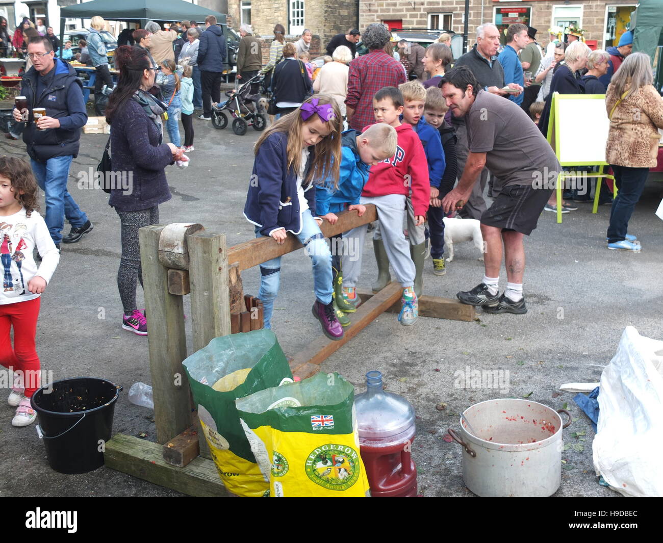 Children sitting on a giant wooden press to weigh it down in order to ...
