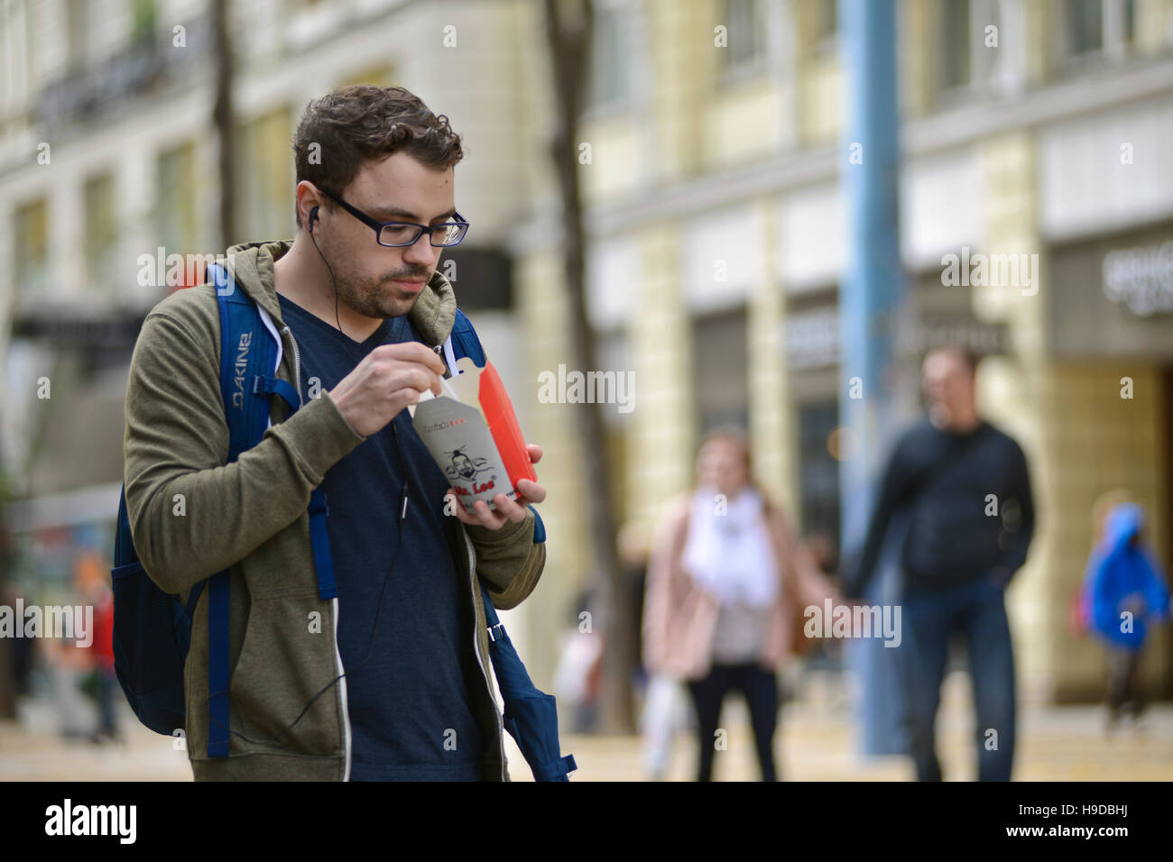 A man eating chinese food while walking down the street Stock Photo - Alamy