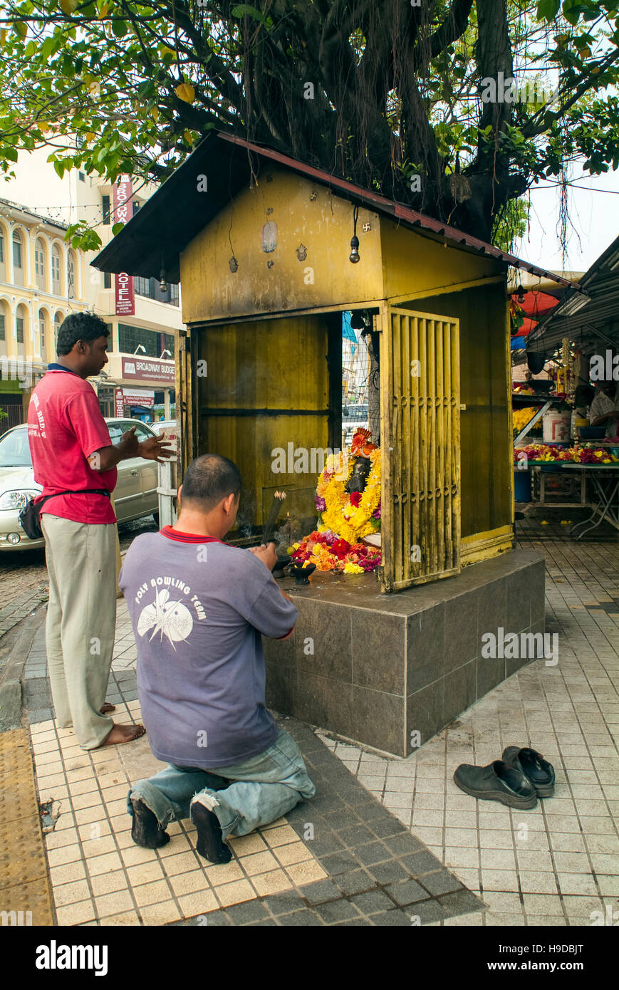 A Chinese and an Indian man pray to a shrine dedicated to the Hindu god ...