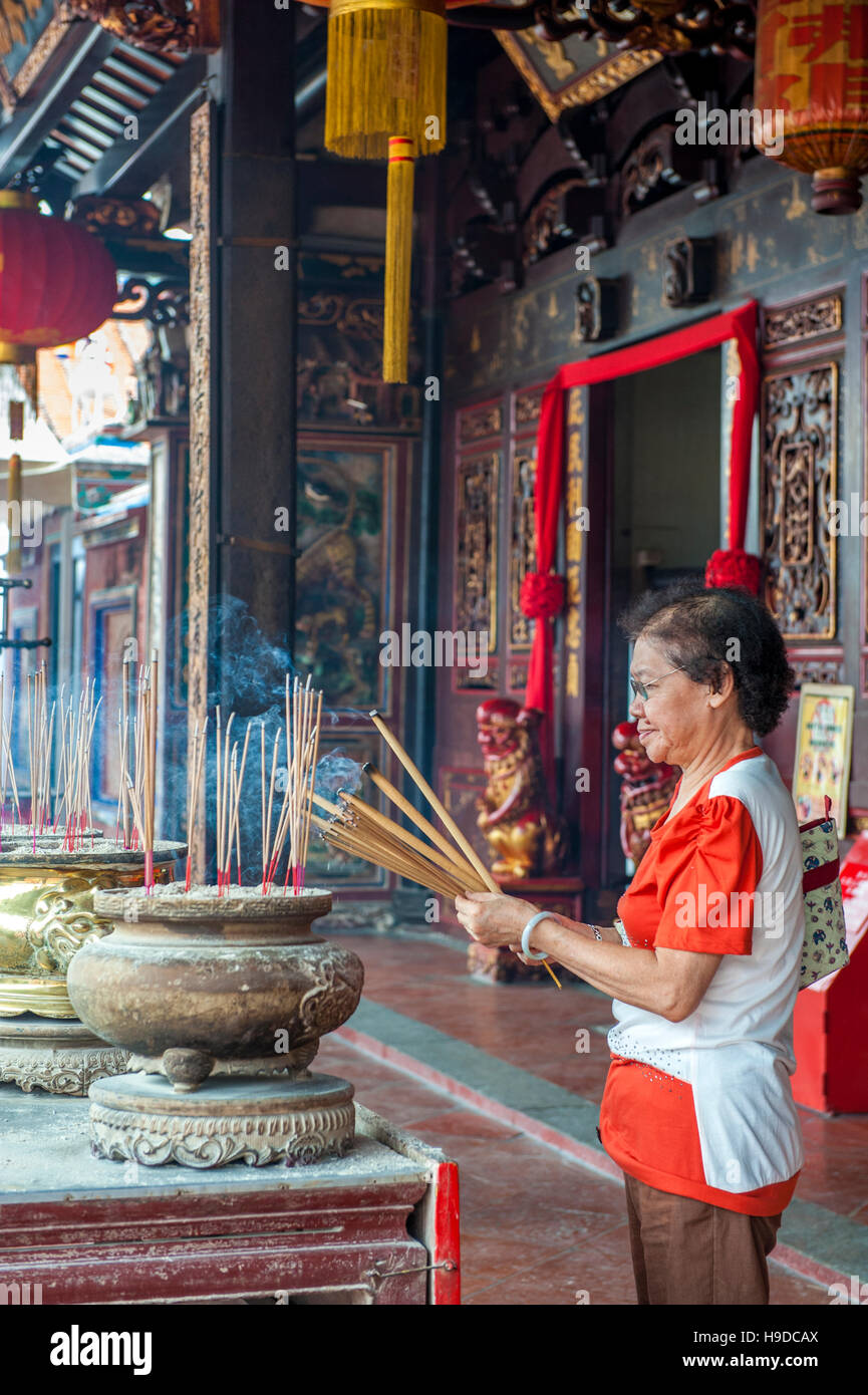 A woman praying at a Chinese temple in Malacca, the World Heritage ...