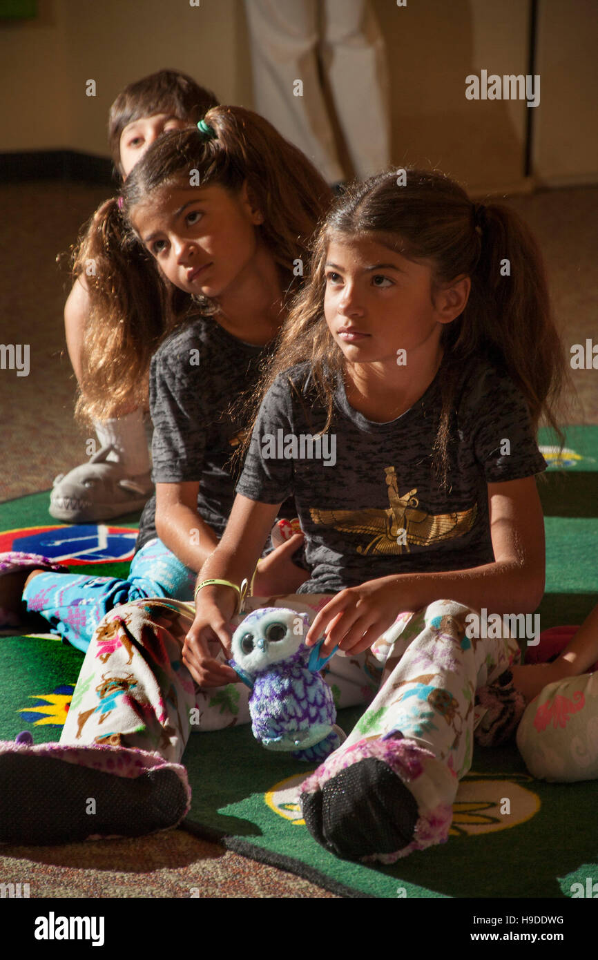 Two pajama-clad sisters listen entranced to a concert by a folk singer ...
