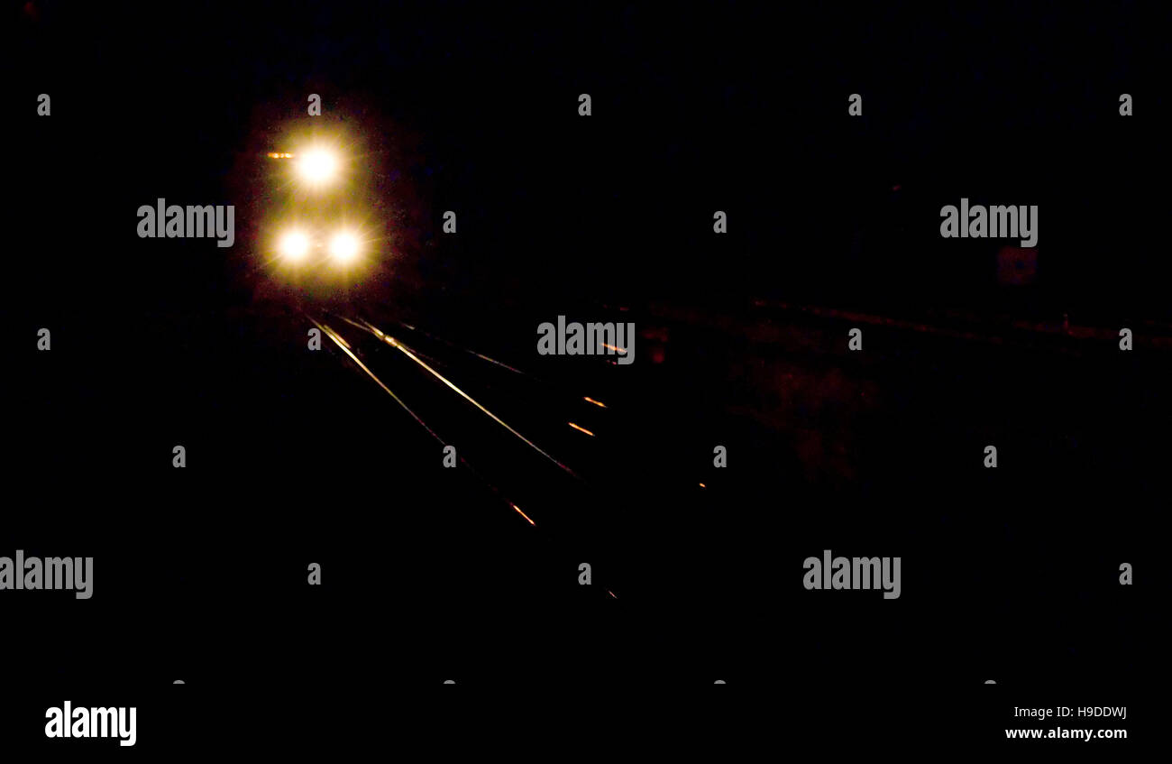 The three headlights of a freight train reflect dramatically on ...