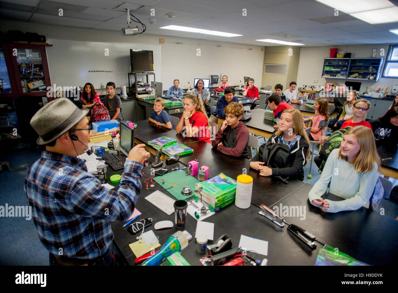 An Asian American science teacher lectures an attentive middle school ...