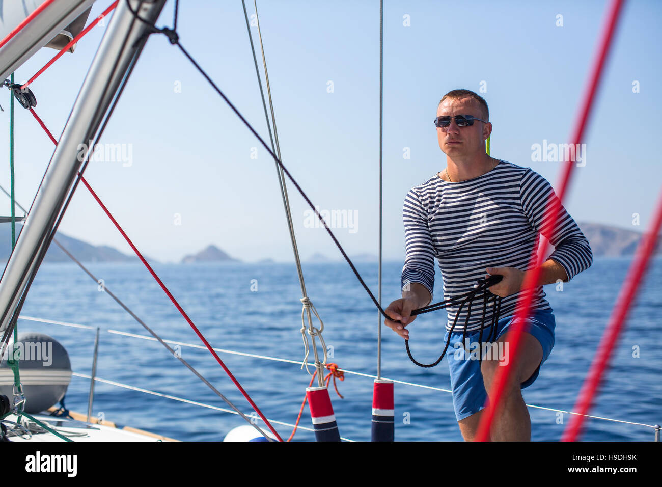 Young man skipper at his sail boat, controls ship during sea yacht race ...