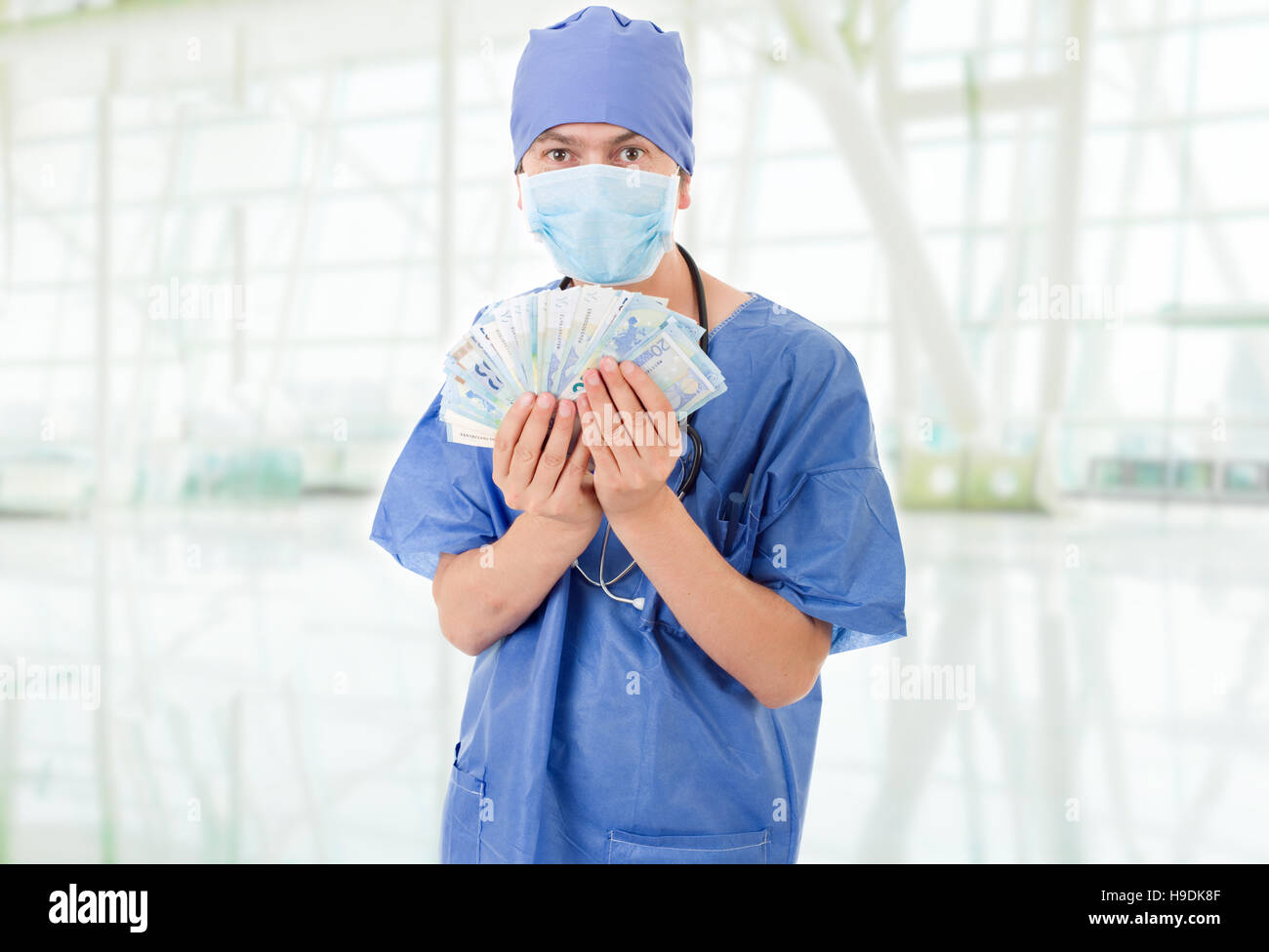 Happy male doctor holding bank notes, at the hospital Stock Photo - Alamy