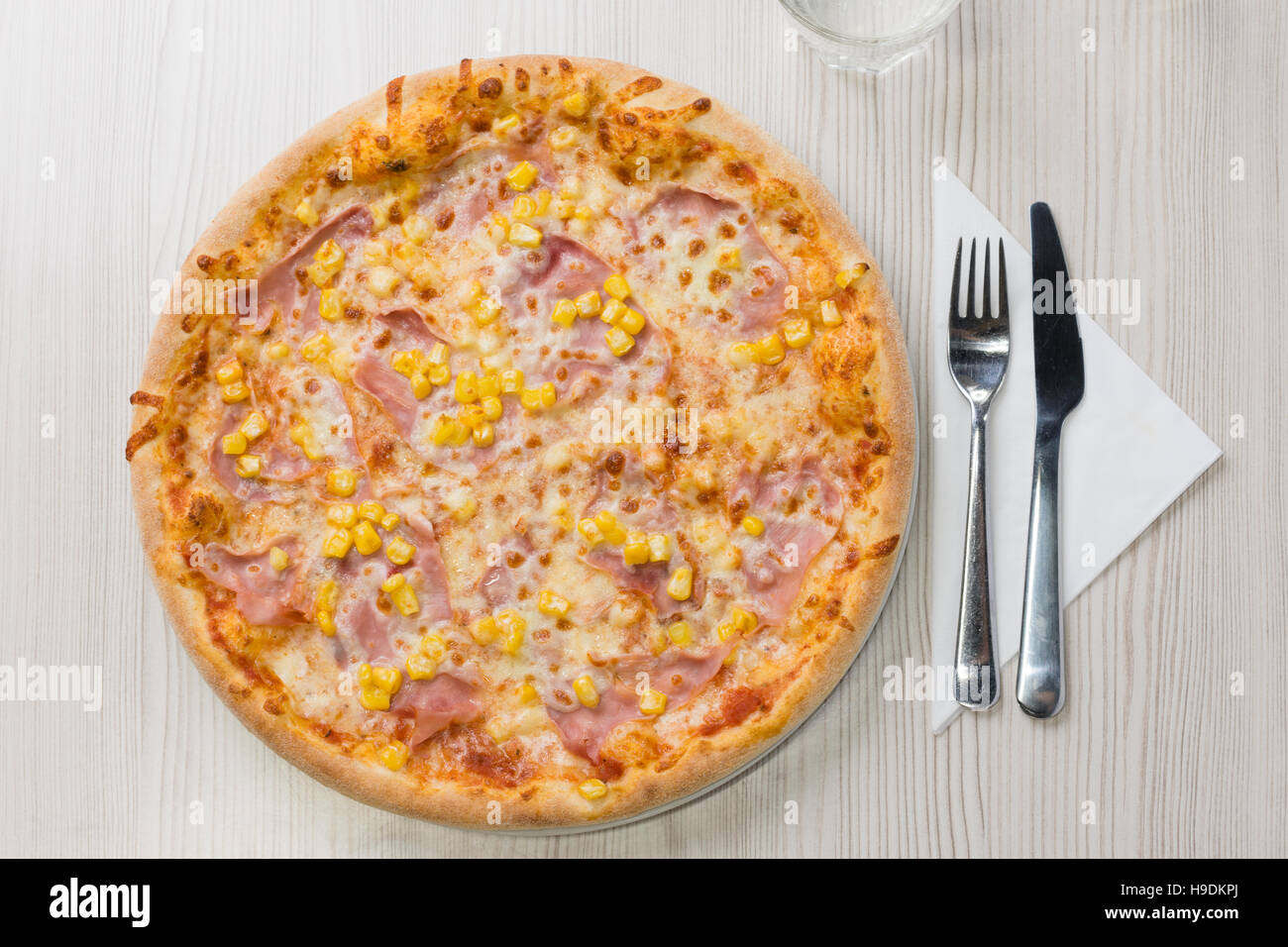 Pizza with ham and corn on the table Stock Photo - Alamy