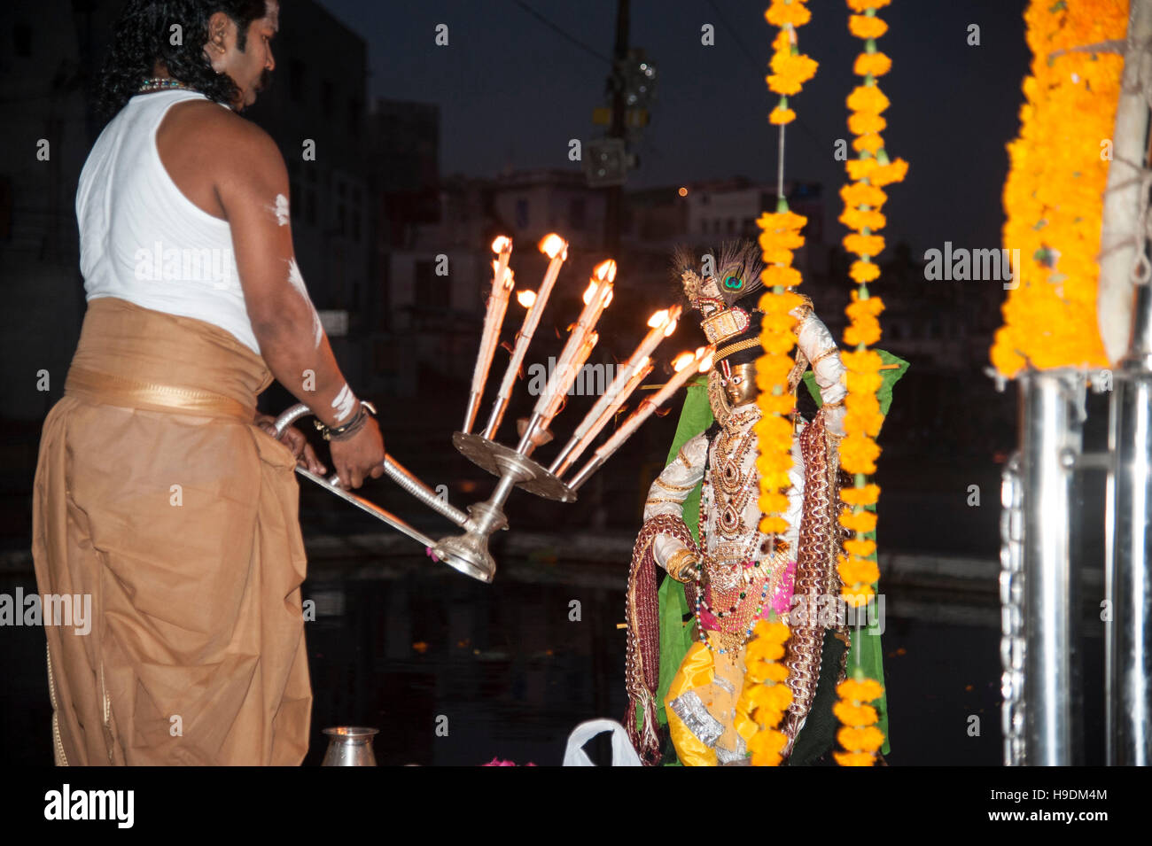 Hindu priest performs the Aarti ritual in front of lord krishna idol at ...