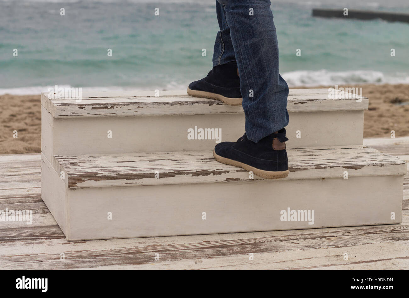 Man's foot walking up on wooden ladder. Sea on background Stock Photo ...