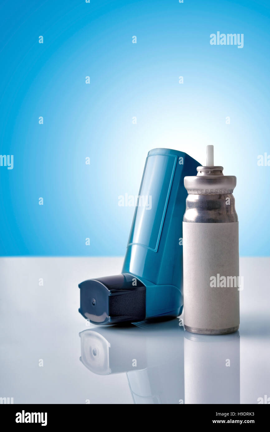 Cartridge and blue medicine inhaler on white glass table with blue ...